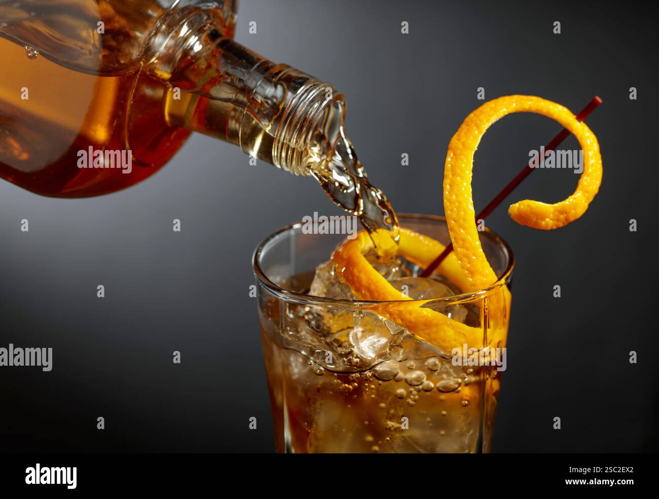 Whiskey or bourbon pouring into a glass with ice. Old-fashioned ...
