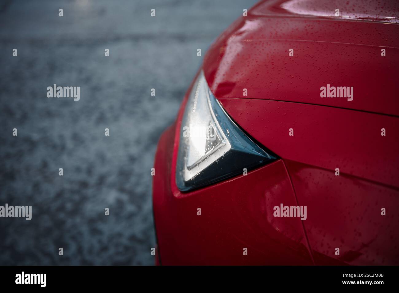 Red modern car with bright LED headlights - front fender view. Blurry ...
