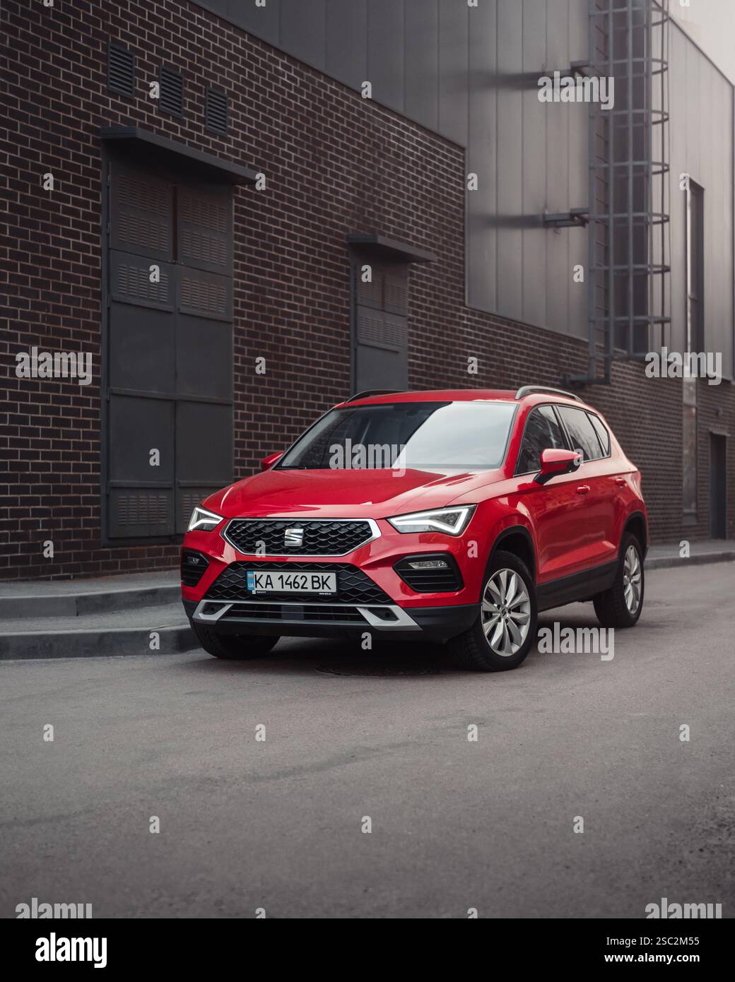 Red SEAT Ateca in front of brown brick building. Front three quarter ...
