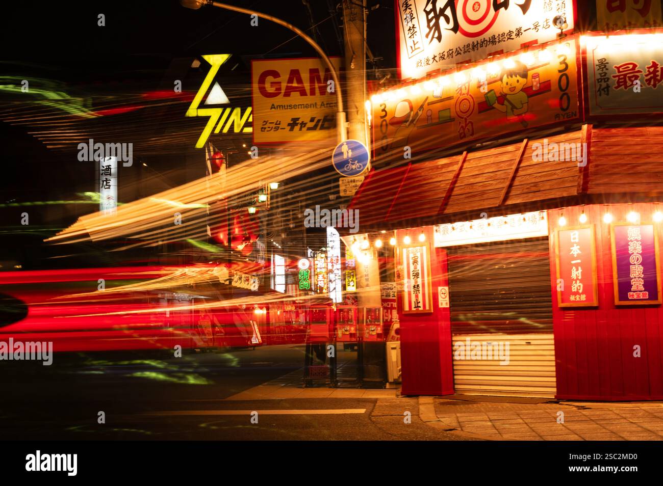 Long exposure shot of a Japanese city street at night, featuring neon ...