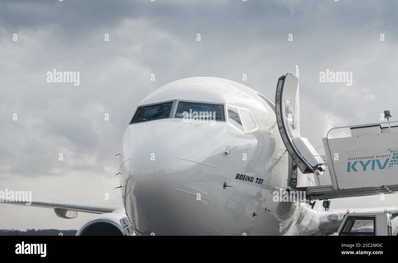 Boeing 737 (UR-UBA) parked near the gate at the airport, close up view. Nose section of white ...