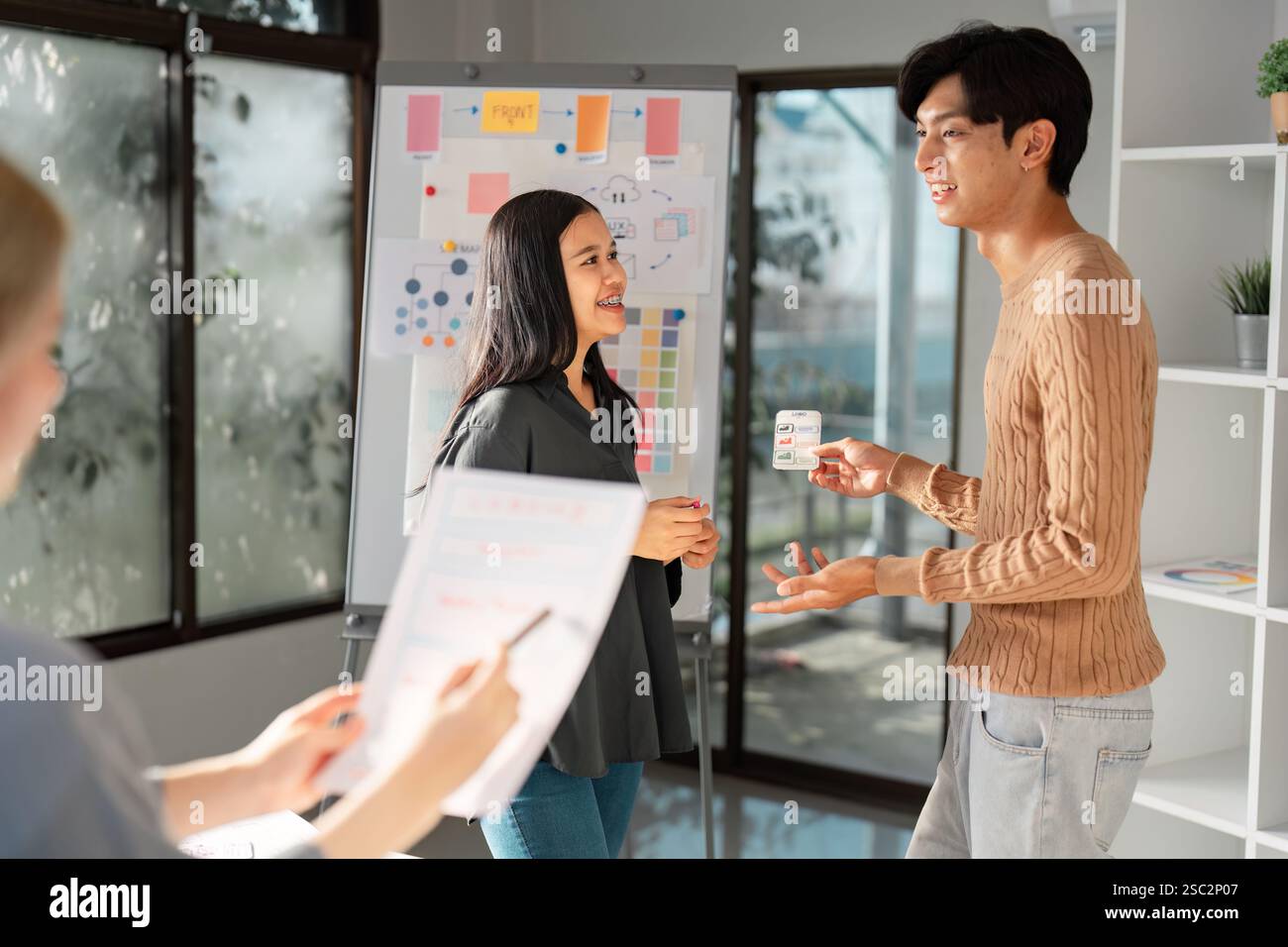 UX UI designer presenting ideas to a client with visuals in a bright ...