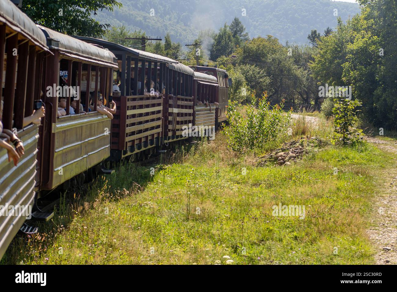 People tourists in carriages travel by Carpathian tram in mountain ...