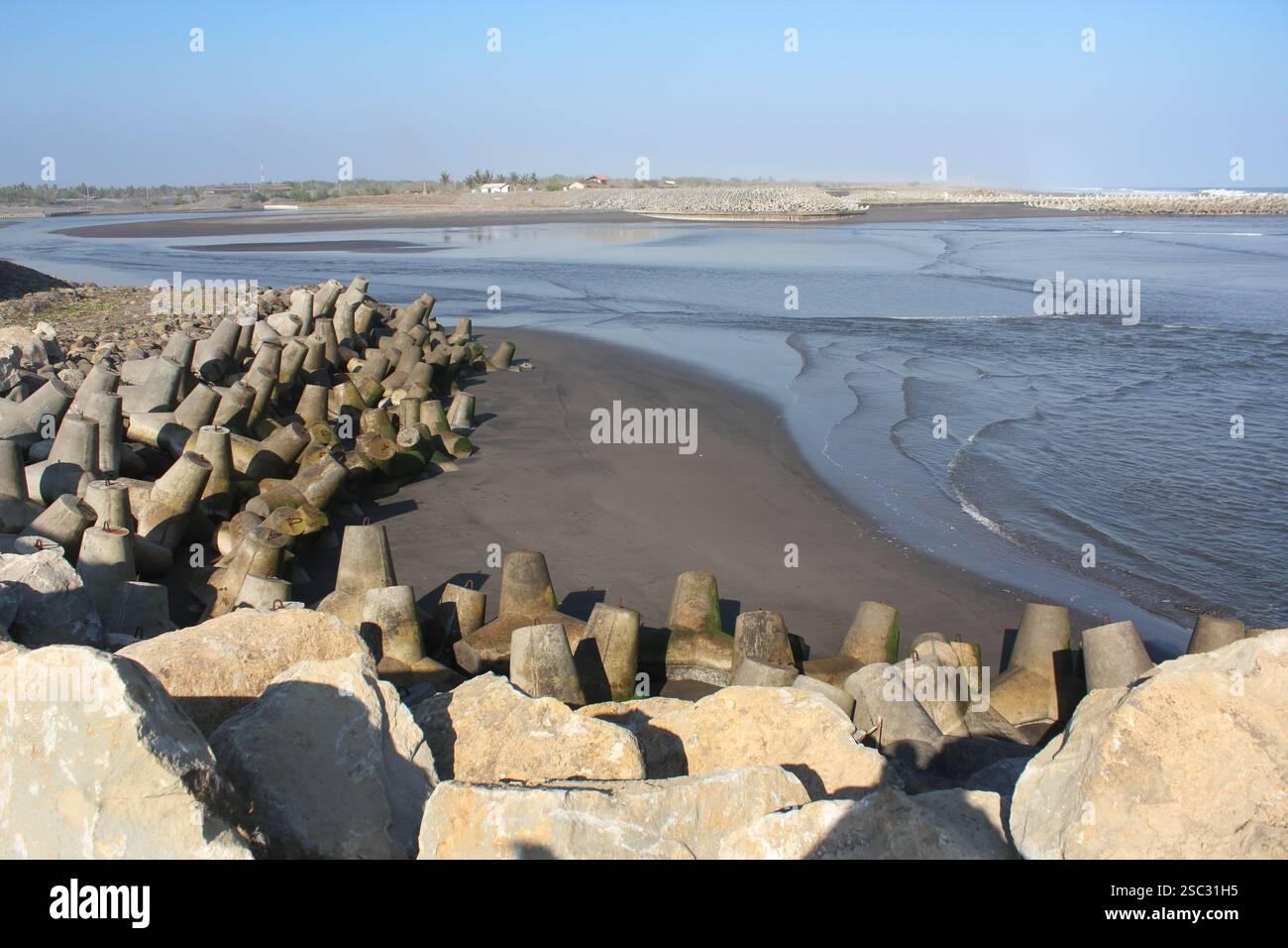 The image depicts well-arranged tetrapod structures on a sandy ...