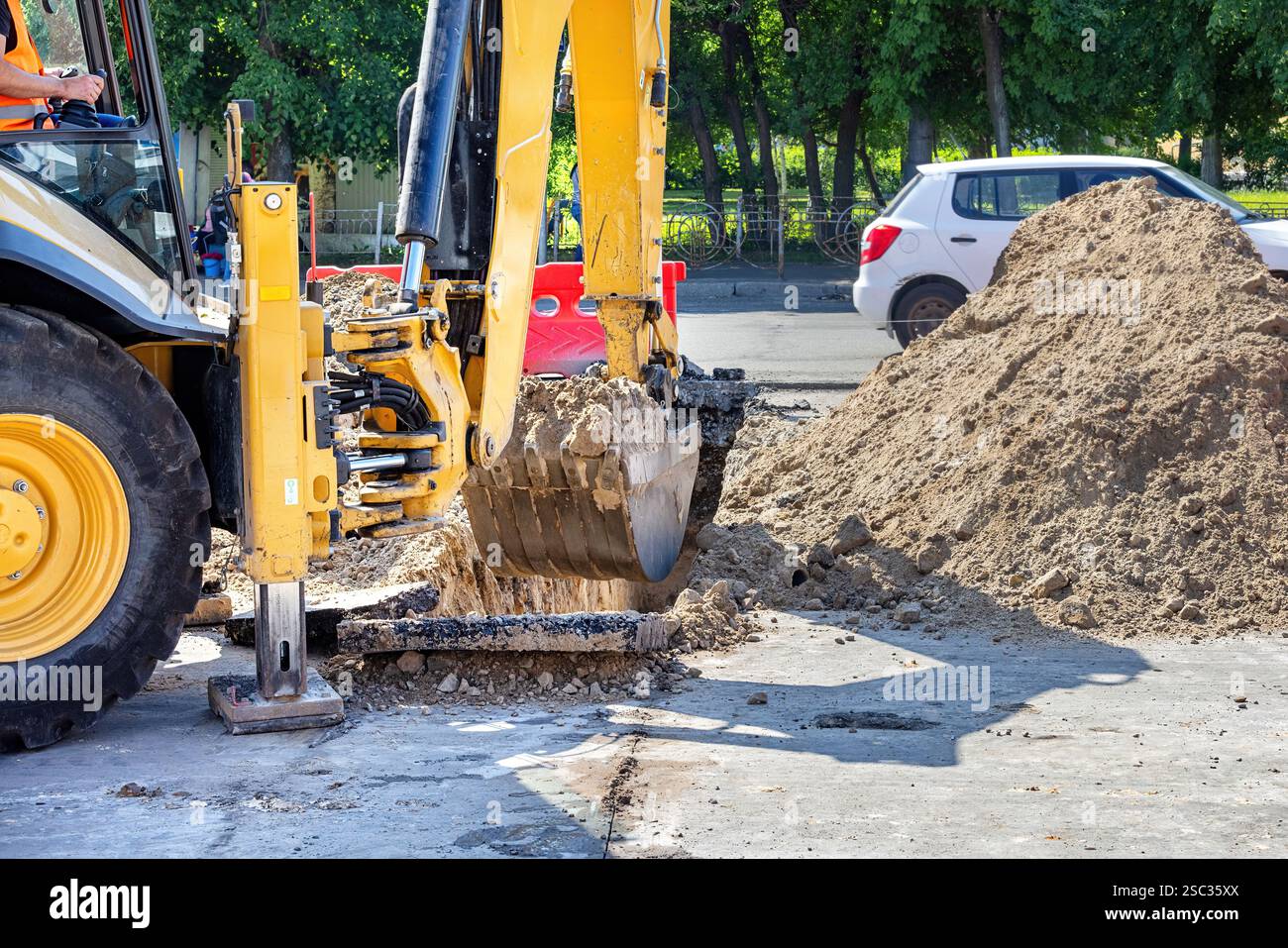 Heavy machinery painstakingly removes asphalt on a busy city street ...