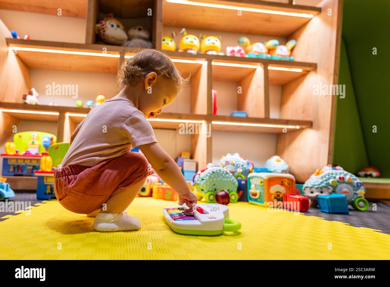 Child exploring music and learning activities with a piano and toys in ...