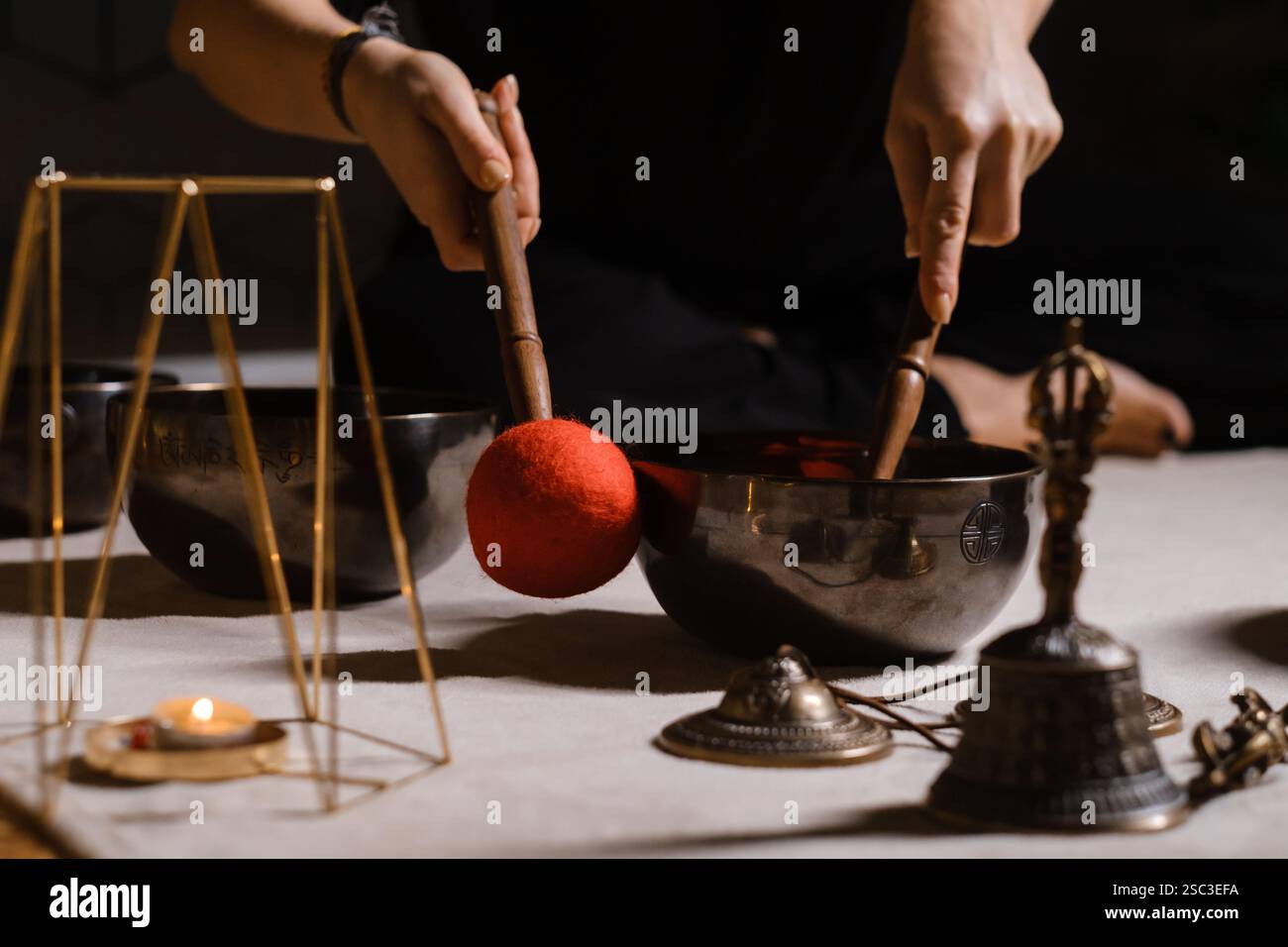In a peaceful indoor space, a person skillfully plays singing bowls ...
