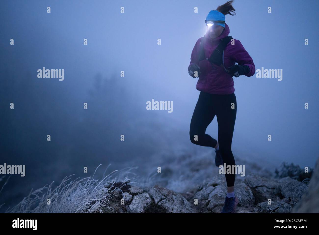 Determined Woman Trail Running at Night, Illuminated by a Headlamp in ...