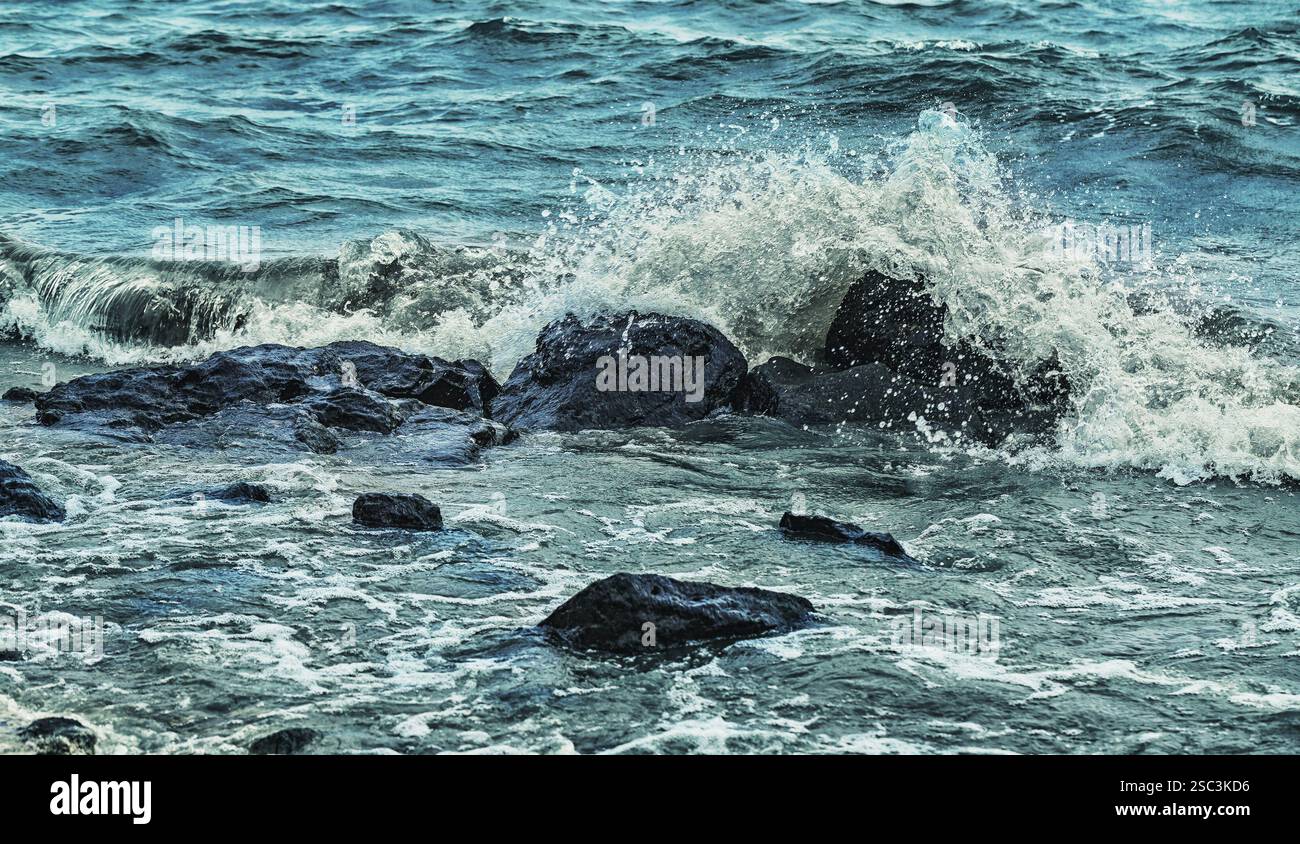 sea surf washes over the coastal black stones Stock Photo - Alamy