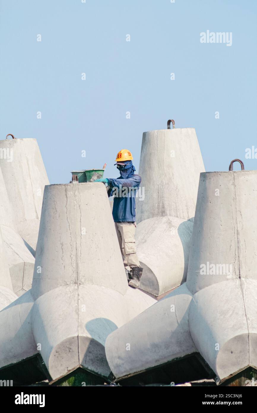 A focused construction worker wearing safety gear is meticulously ...