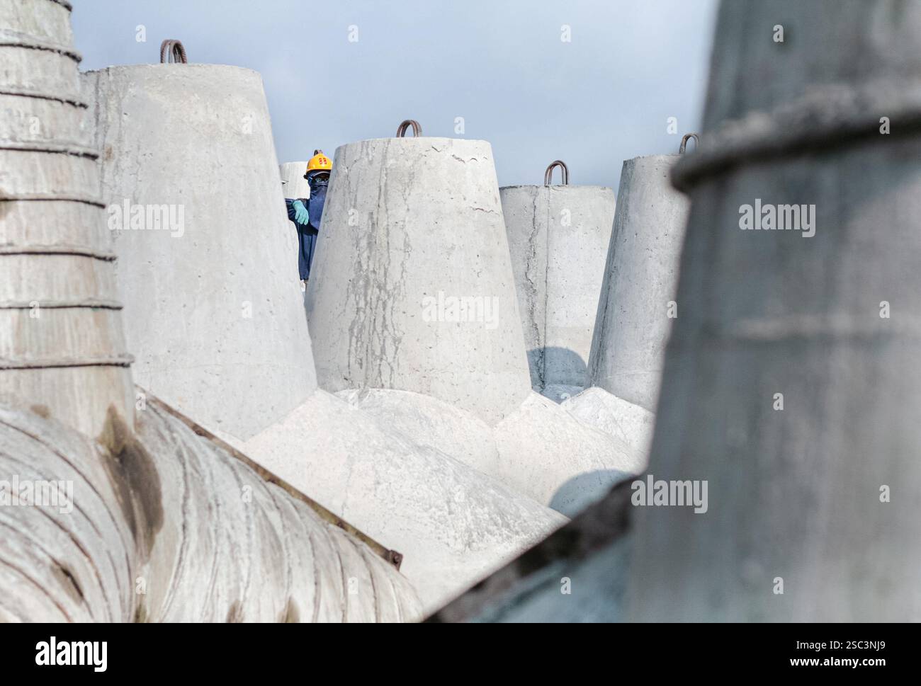 An Indonesian construction worker in a yellow helmet stands confidently ...