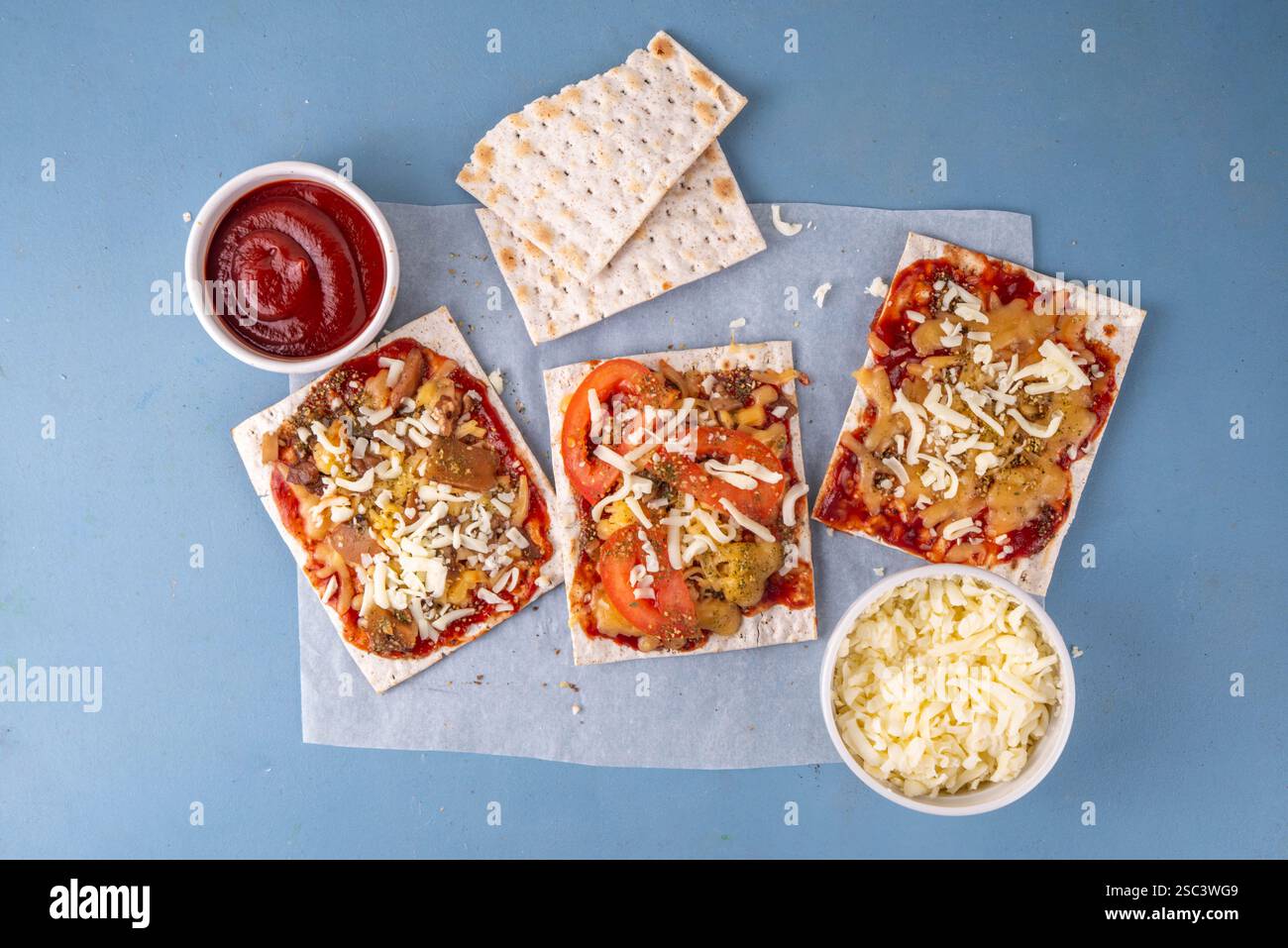 Matzah Pizza on light blue background with ingredients, cheese, tomato ...
