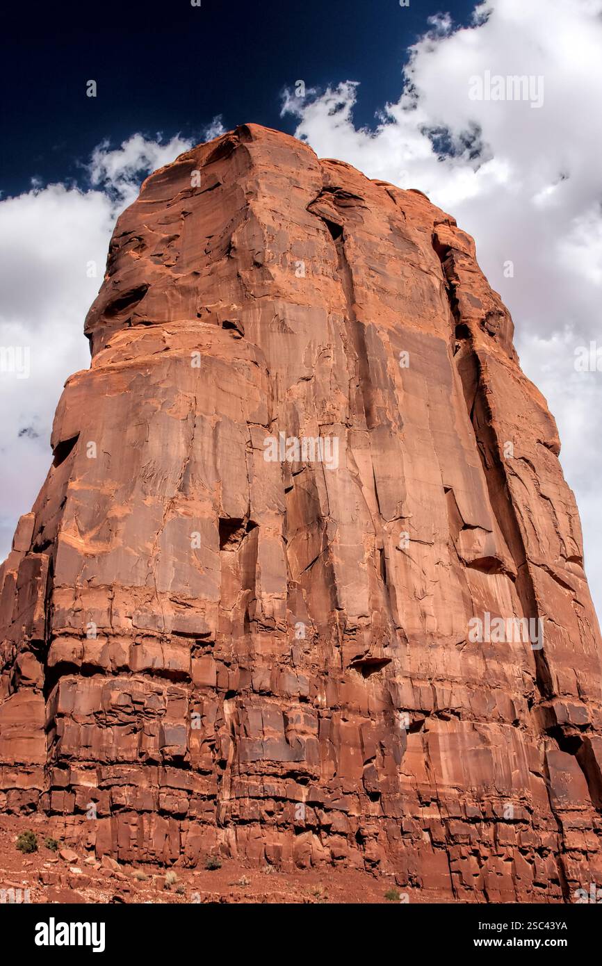 A large rock formation with a cloudy sky in the background. The rock is ...