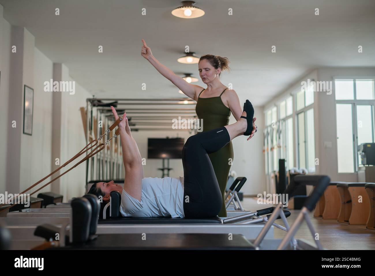 Pilates coach teaching a young student the correct posture on the ...