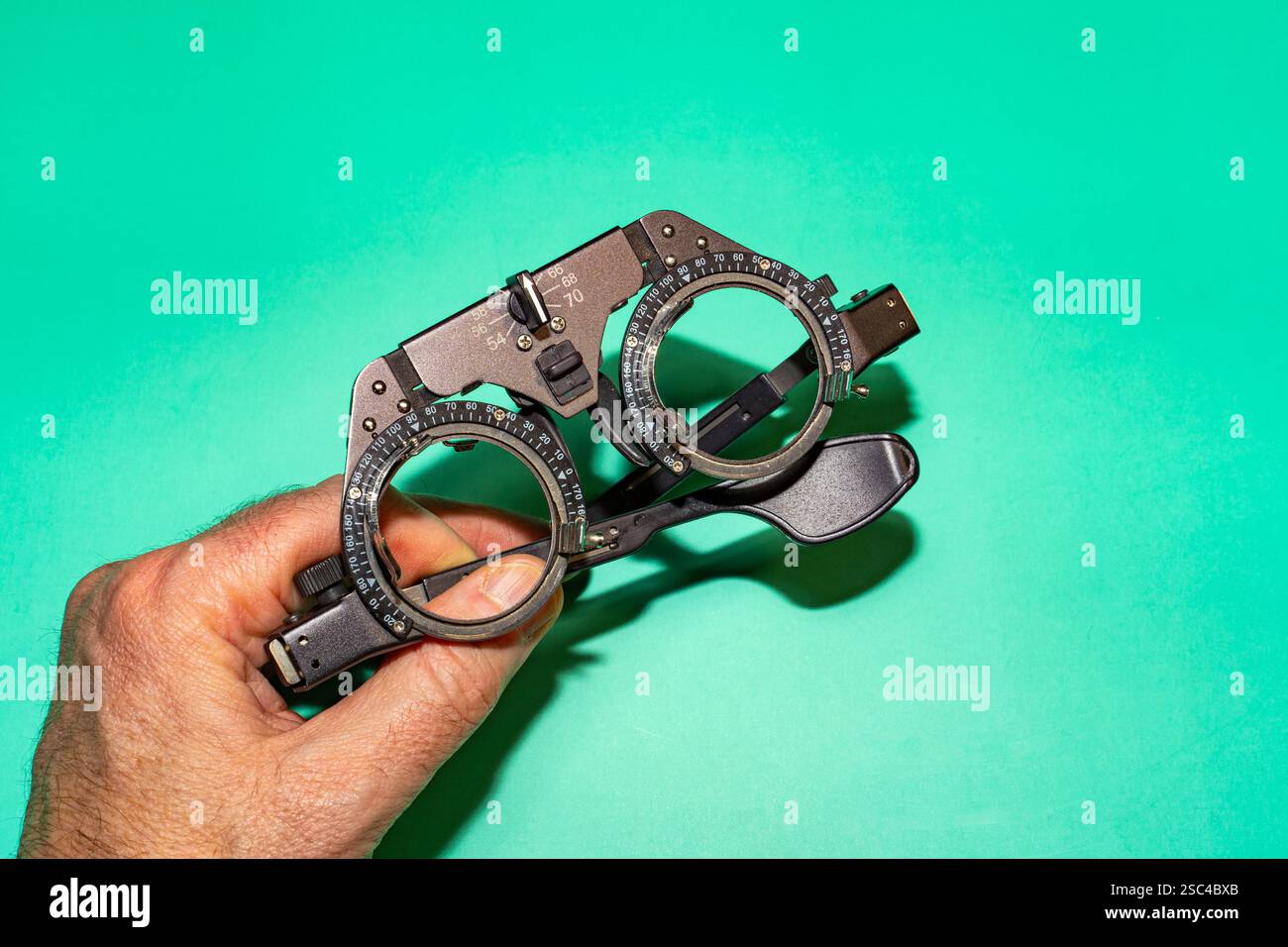 Female hands holding optical device for vision examination on a green ...