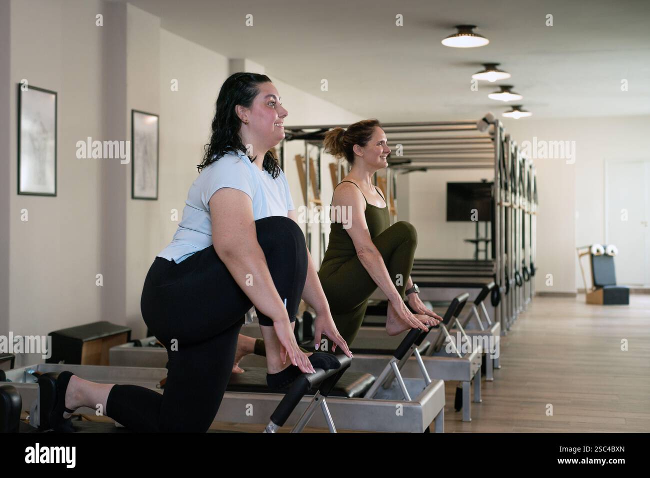 Two women doing Front split on the Pilates reformer Stock Photo - Alamy