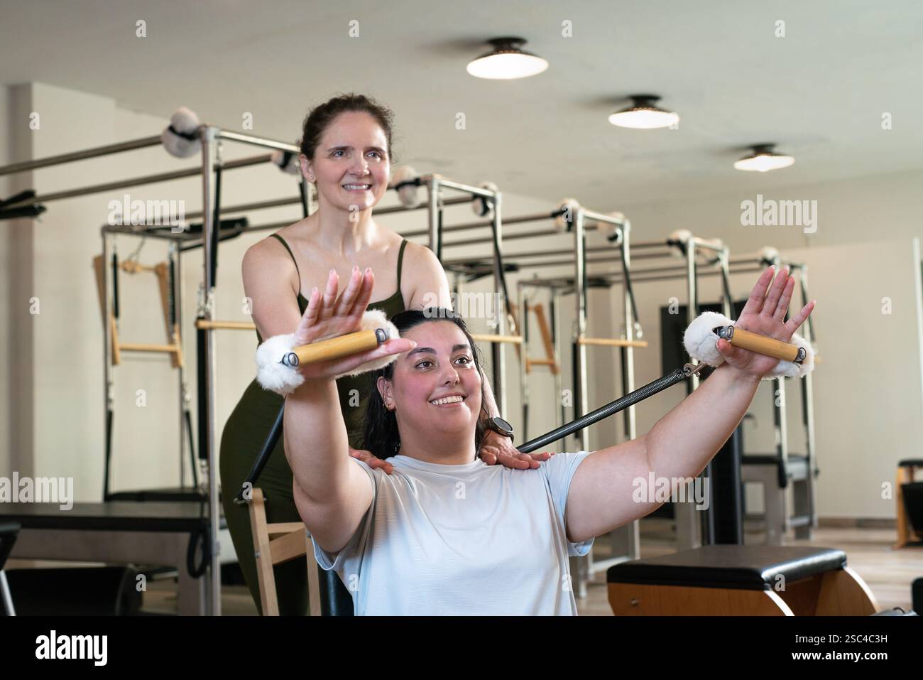 Pilates personal trainer assisting Young woman centering exercise on ...