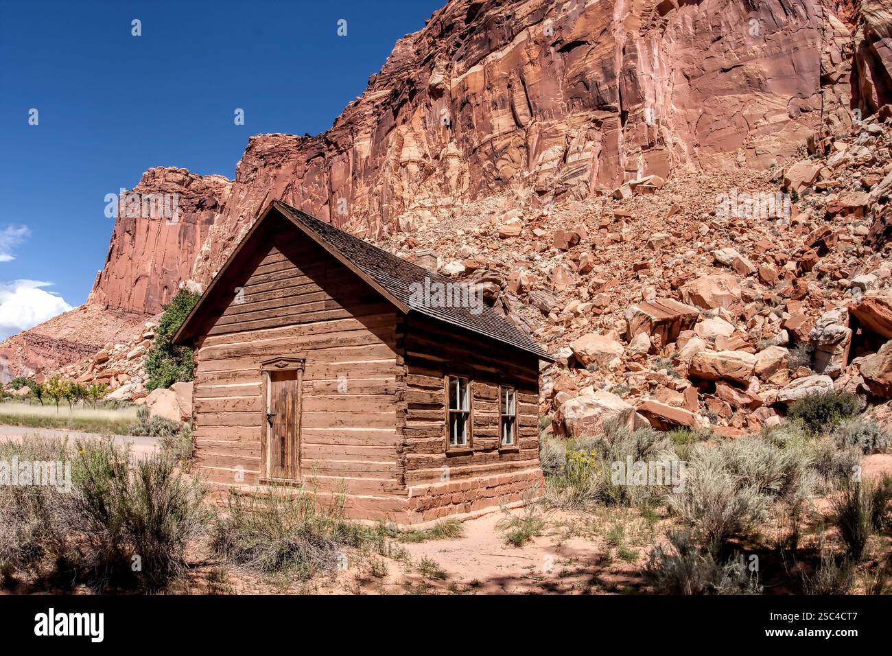 A small log cabin is in the middle of a desert. The cabin is surrounded ...
