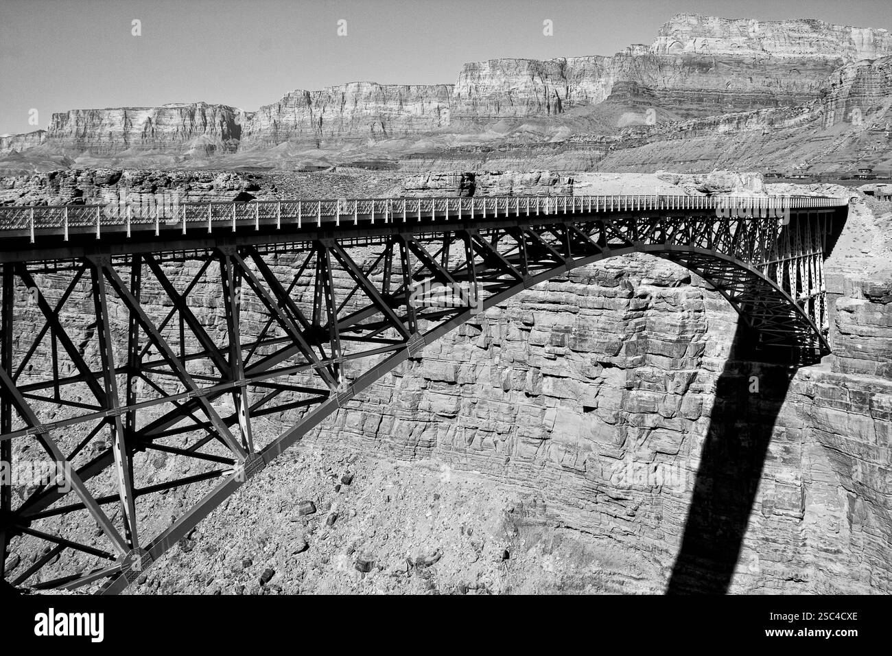 A bridge over a canyon with a shadow on the ground. The bridge is made ...