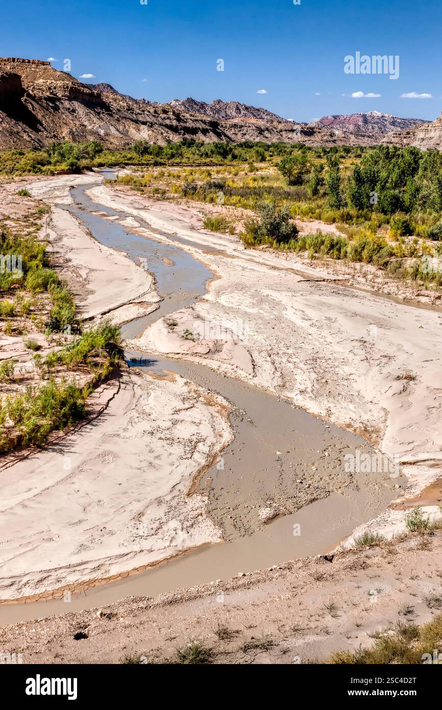 A river is flowing through a desert. The water is muddy and the ground ...