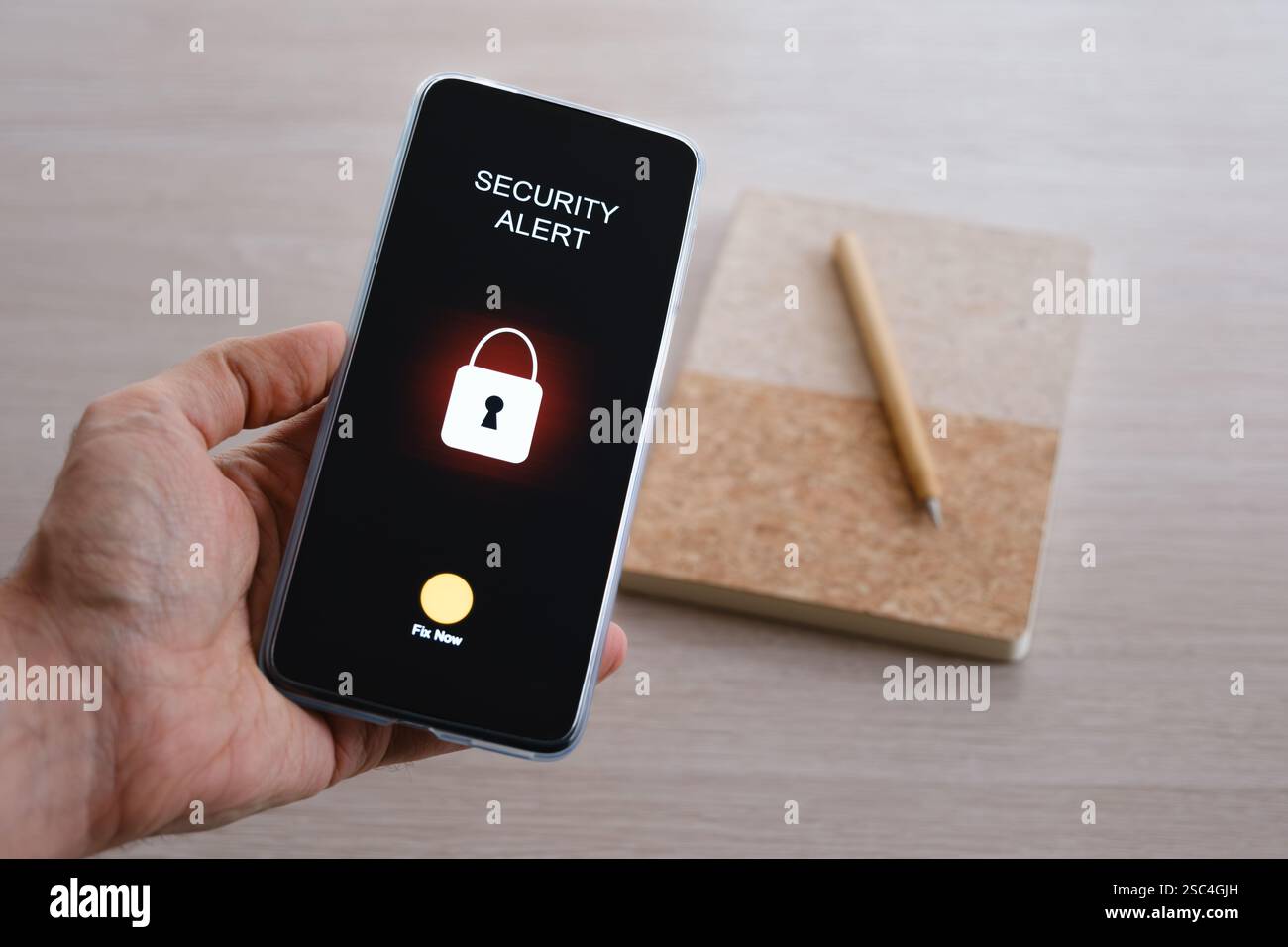 Hand holding smartphone displaying security alert with lock icon Stock Photo - Alamy