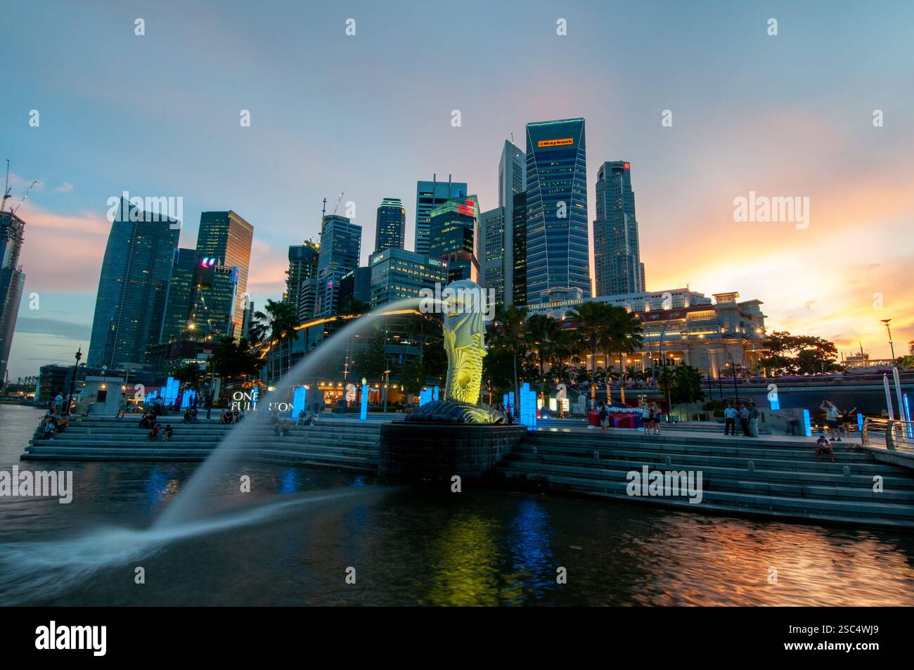 Dusk over the financial district and the symbol of Singapore, the ...