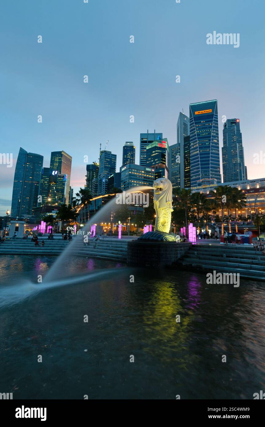 Dusk over the financial district and the symbol of Singapore, the ...