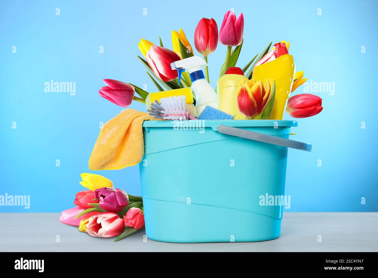 Spring cleaning. Bucket with detergents, supplies and tulips on light ...