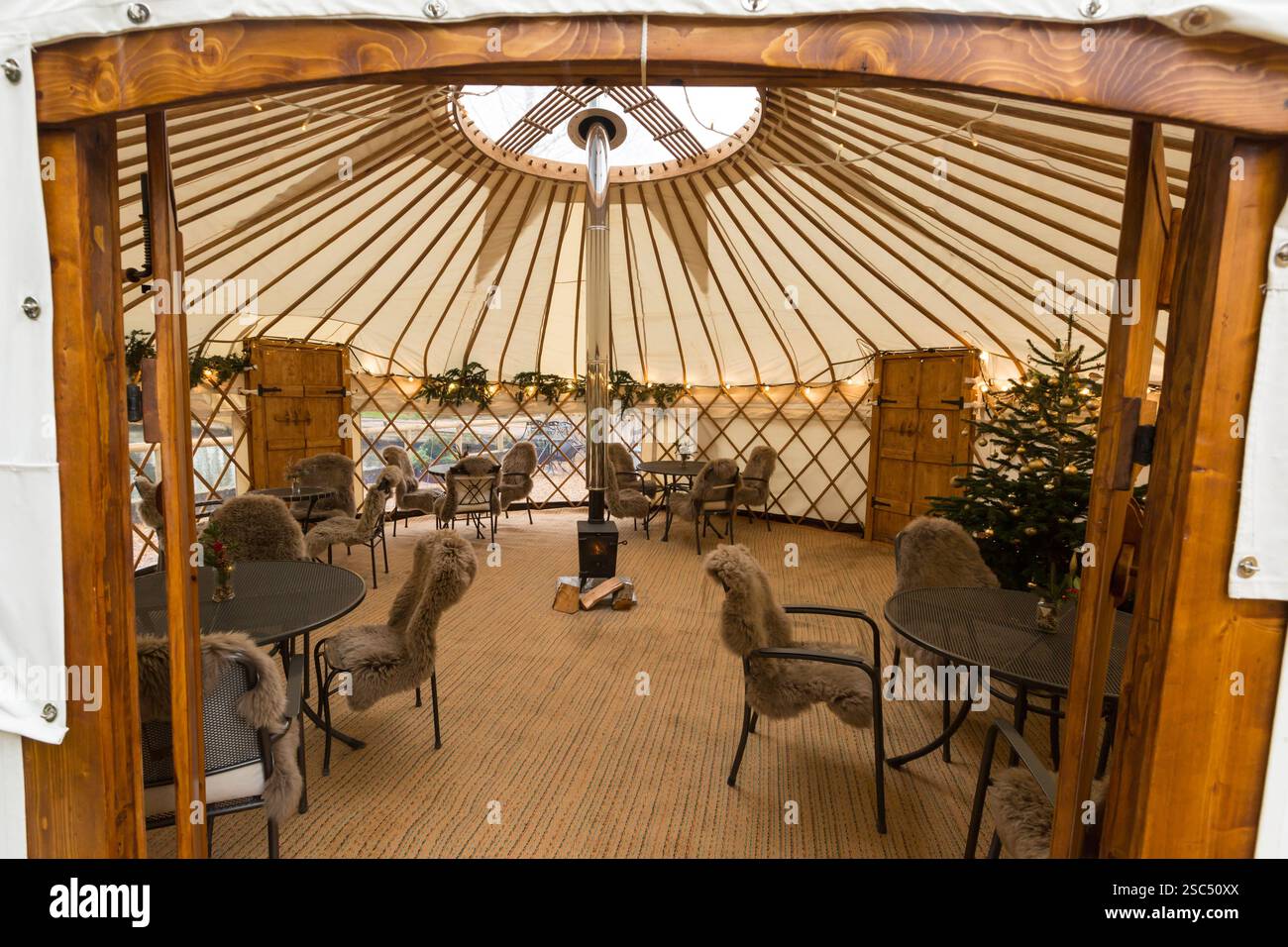 A yurt cafe in the style of a hygge ski lodge, warmed by a wood fired ...