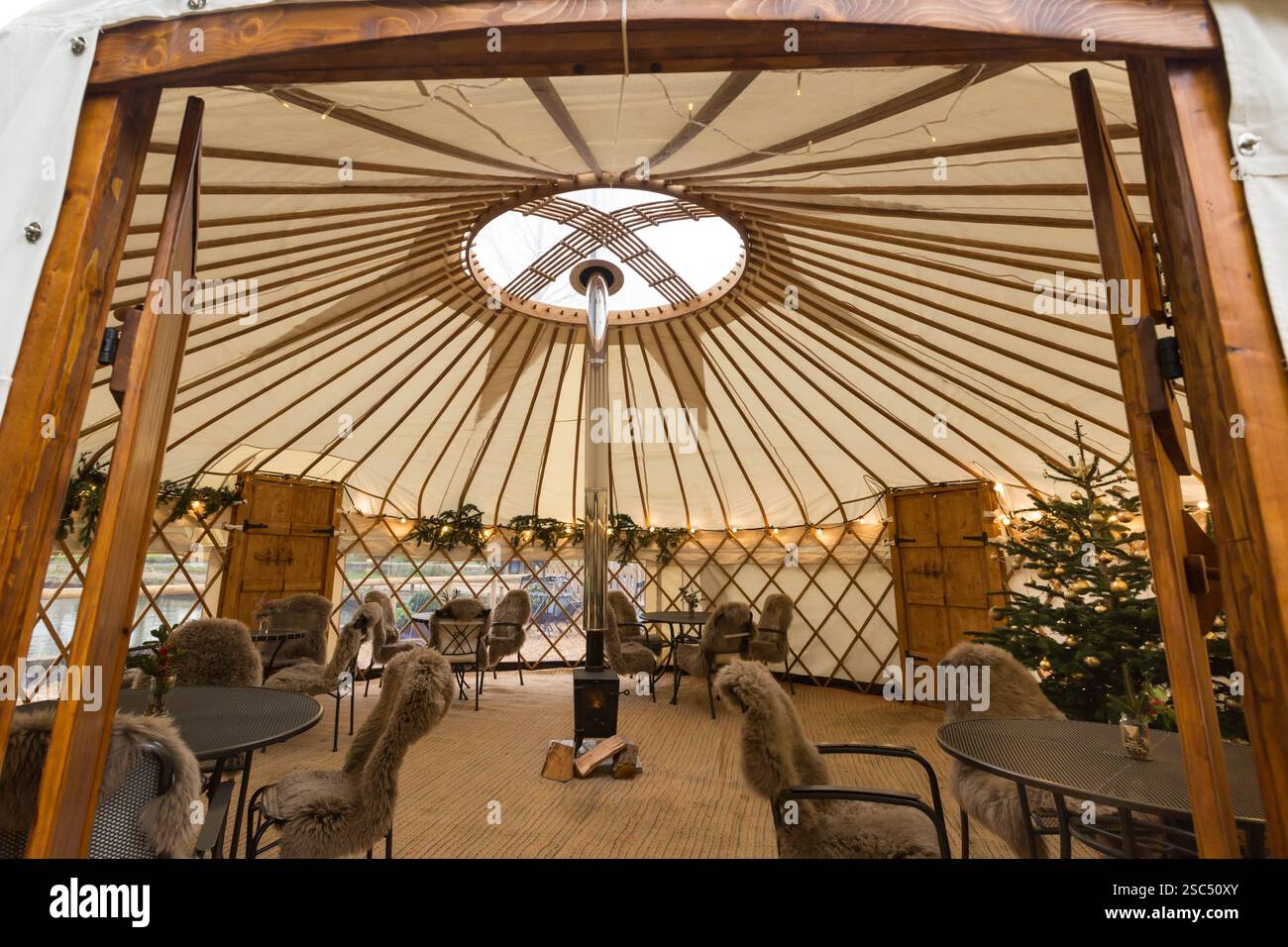 A yurt cafe in the style of a hygge ski lodge, warmed by a wood fired ...