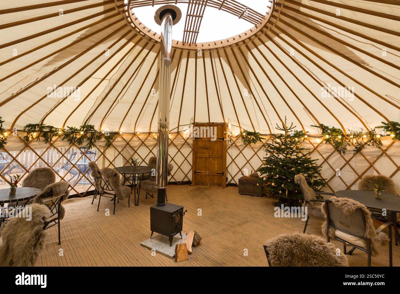 A yurt cafe in the style of a hygge ski lodge, warmed by a wood fired ...