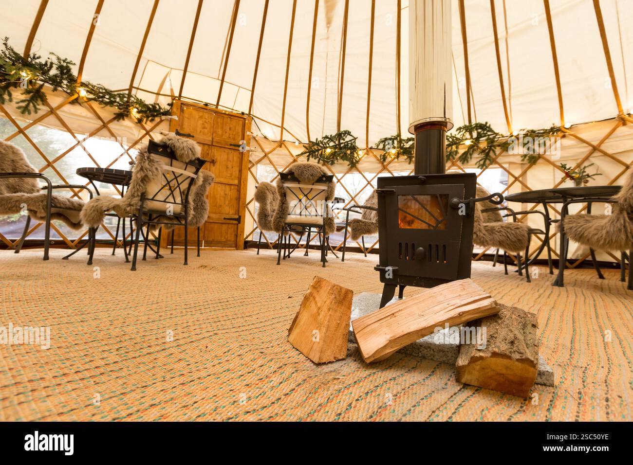 A yurt cafe in the style of a hygge ski lodge, warmed by a wood fired ...