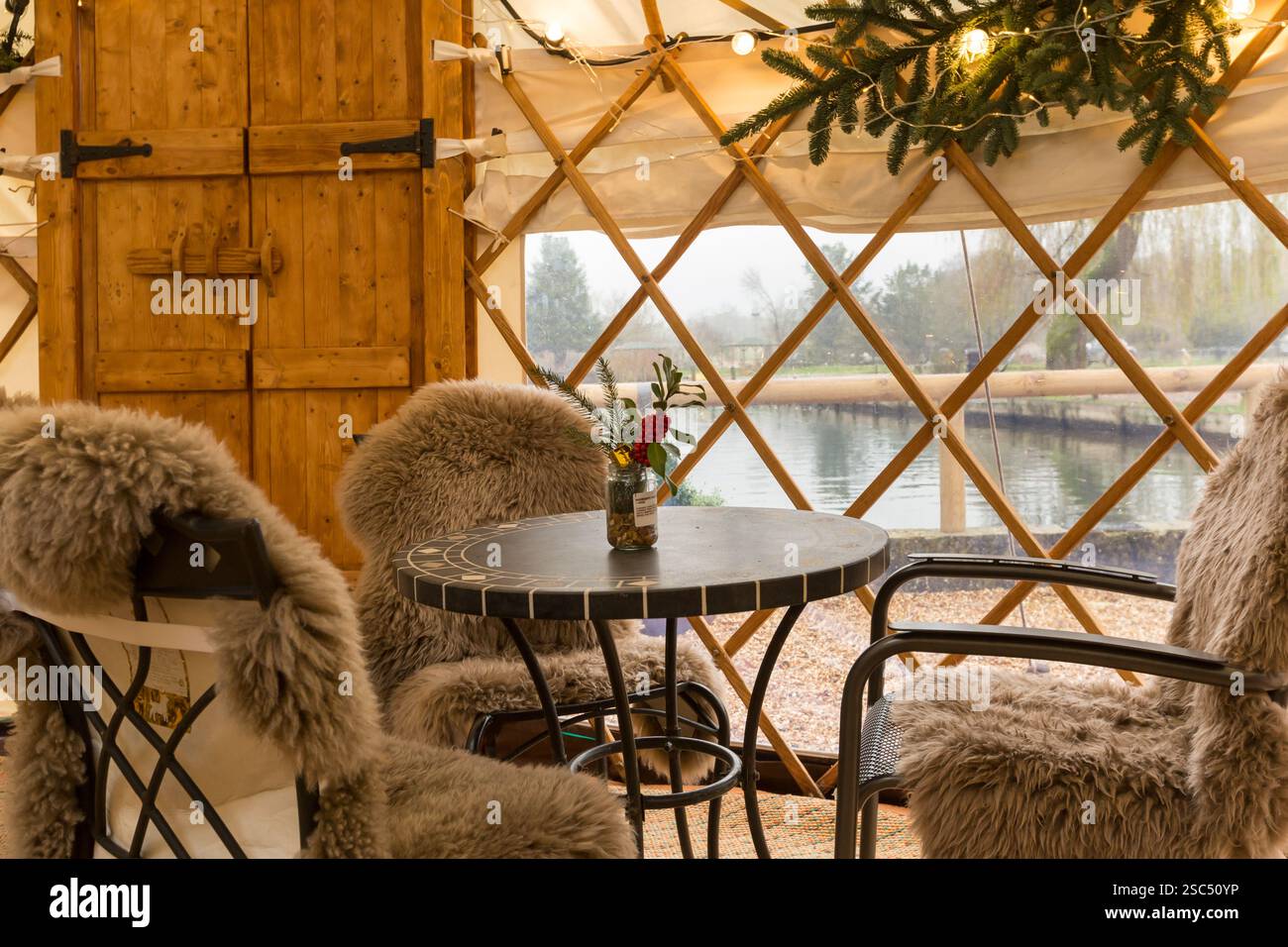 A yurt cafe in the style of a hygge ski lodge, warmed by a wood fired ...