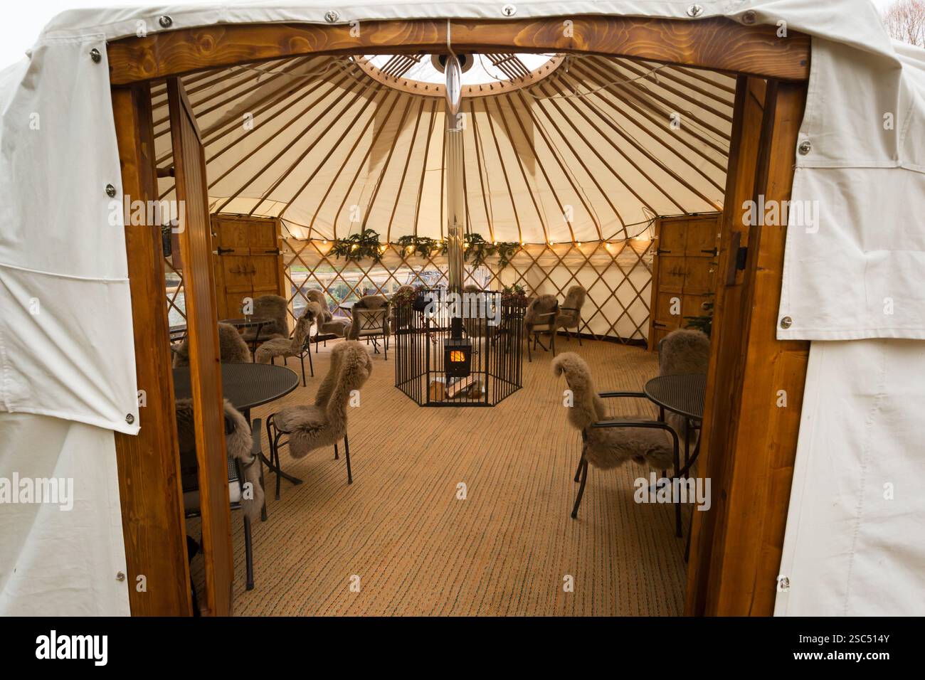 A yurt cafe in the style of a hygge ski lodge, warmed by a wood fired ...