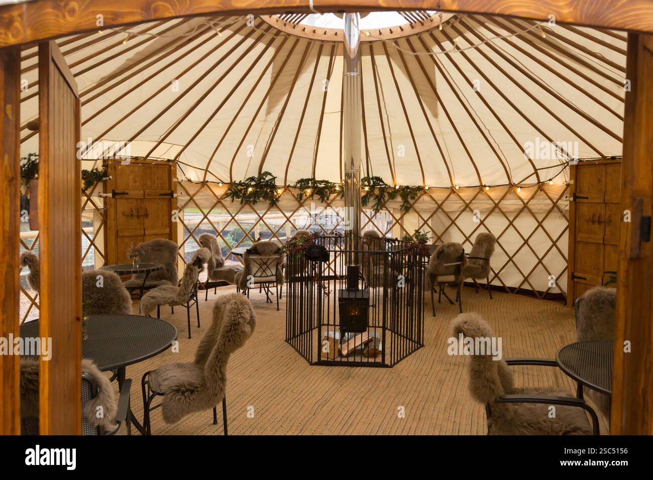 A yurt cafe in the style of a hygge ski lodge, warmed by a wood fired ...