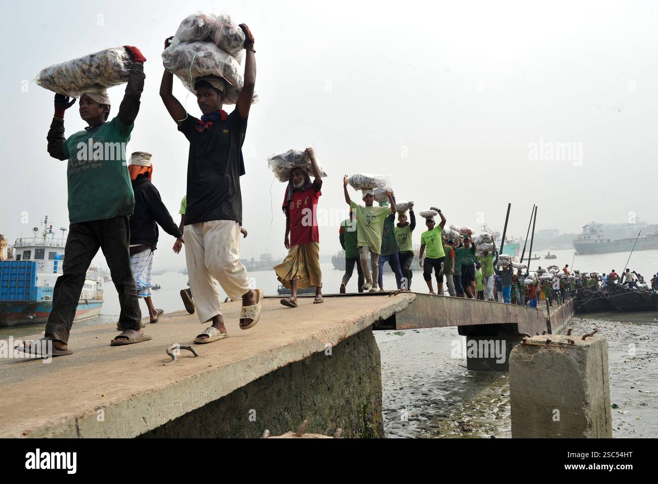 Workers unloading heavy packs of fish from boats at Karnaphuli Ghat in ...