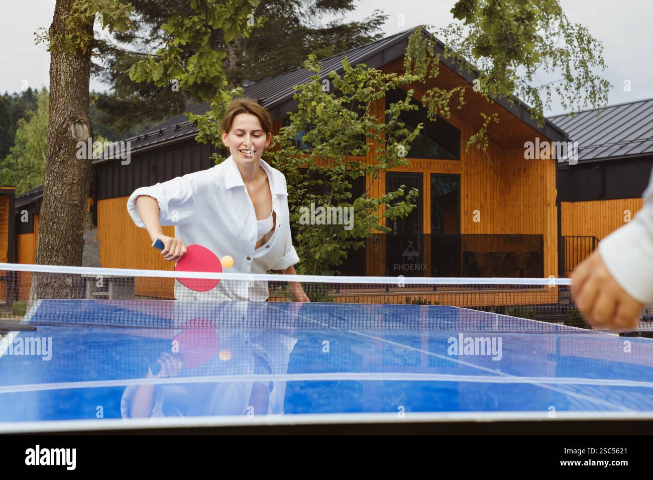 Women enjoy a active game of ping pong in modern outdoor resort ...