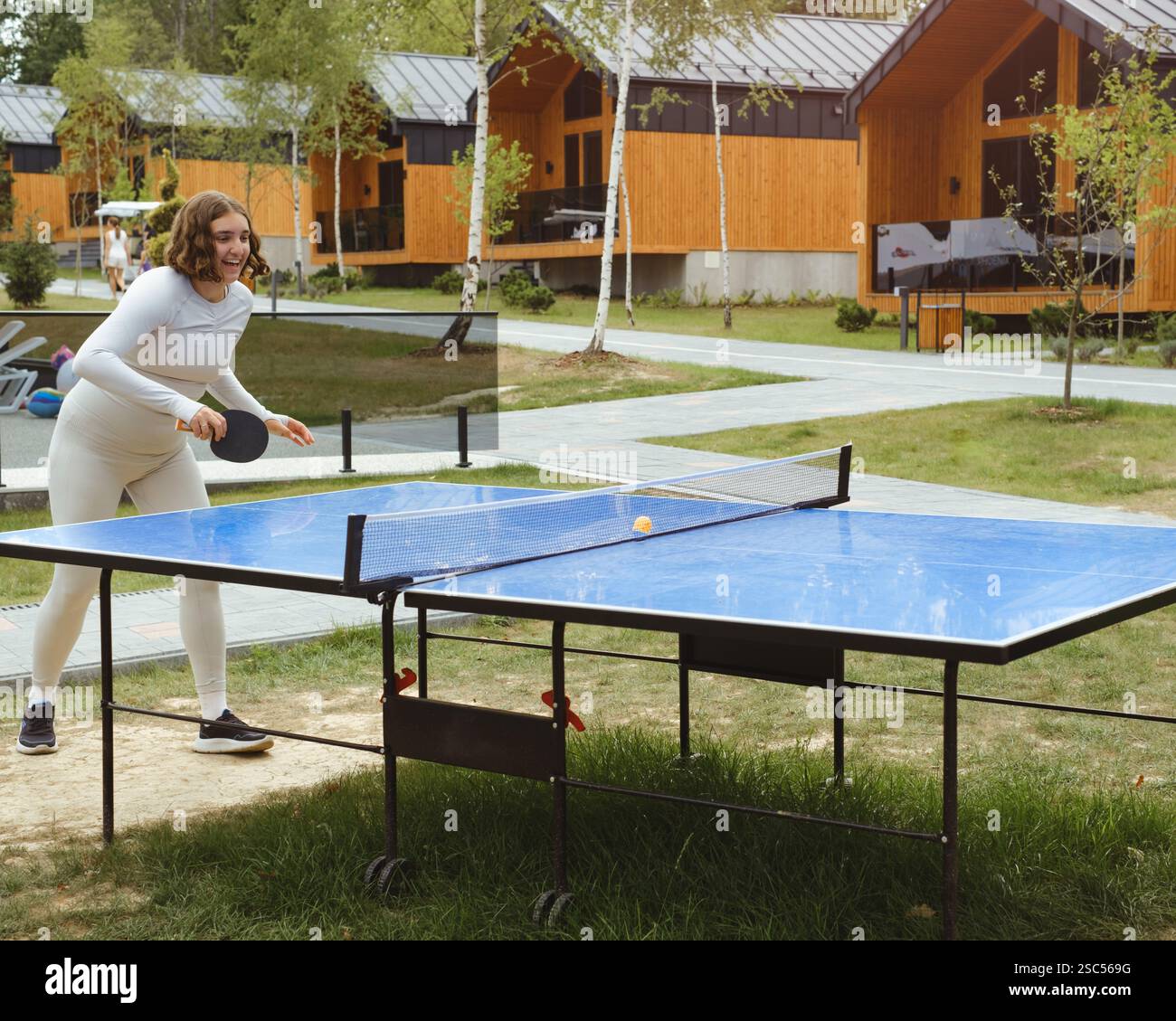 Women enjoy a active game of ping pong in modern outdoor resort ...