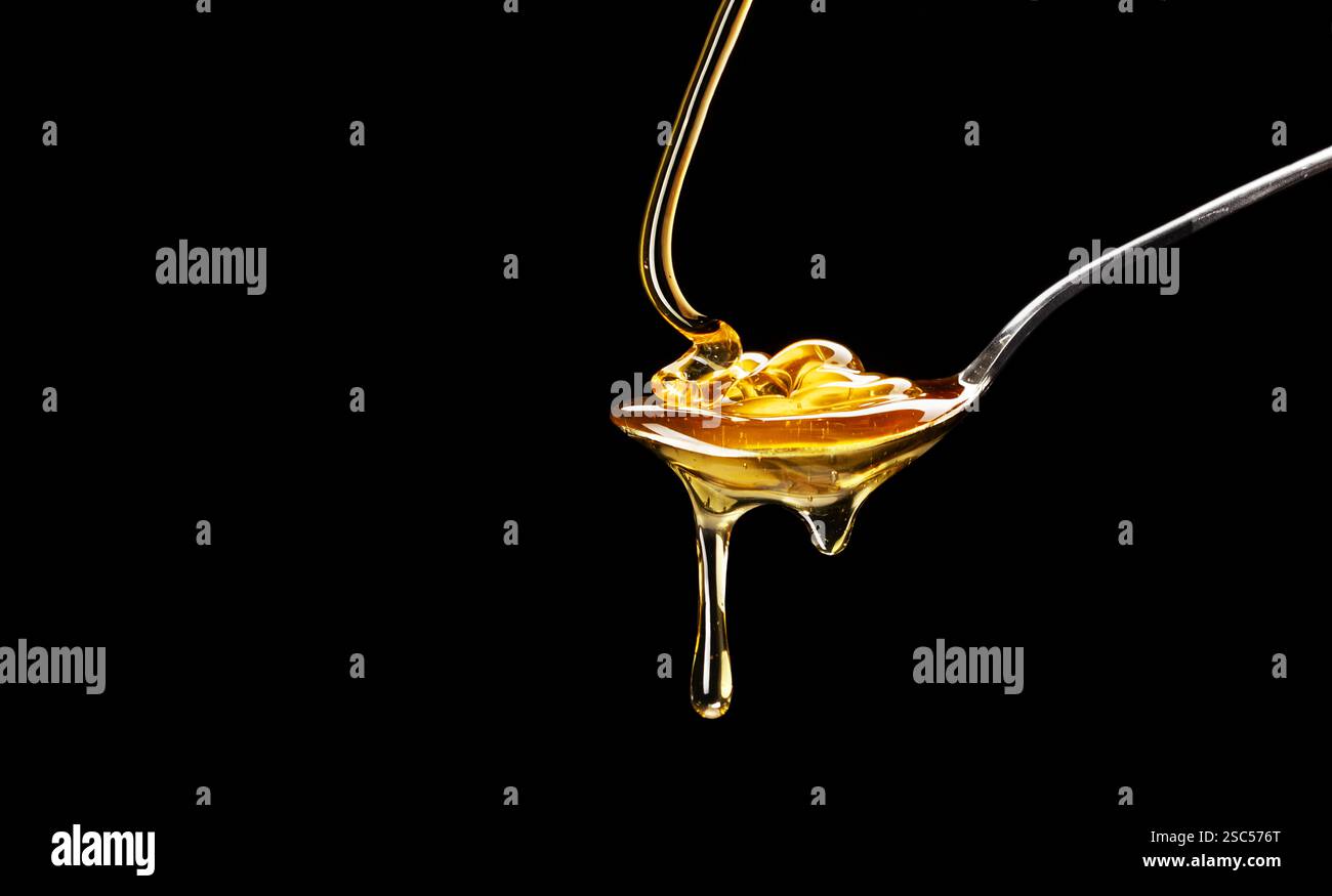 A spoonful of delicious honey spilling on a black background Stock ...