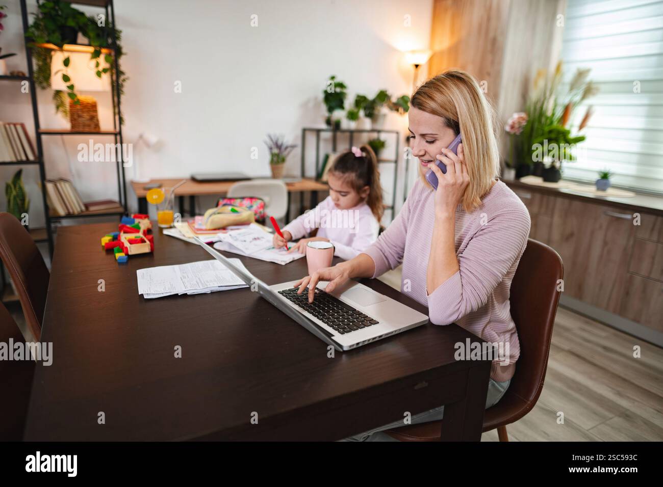 A dedicated mother multitasks with her daughter while managing tasks ...
