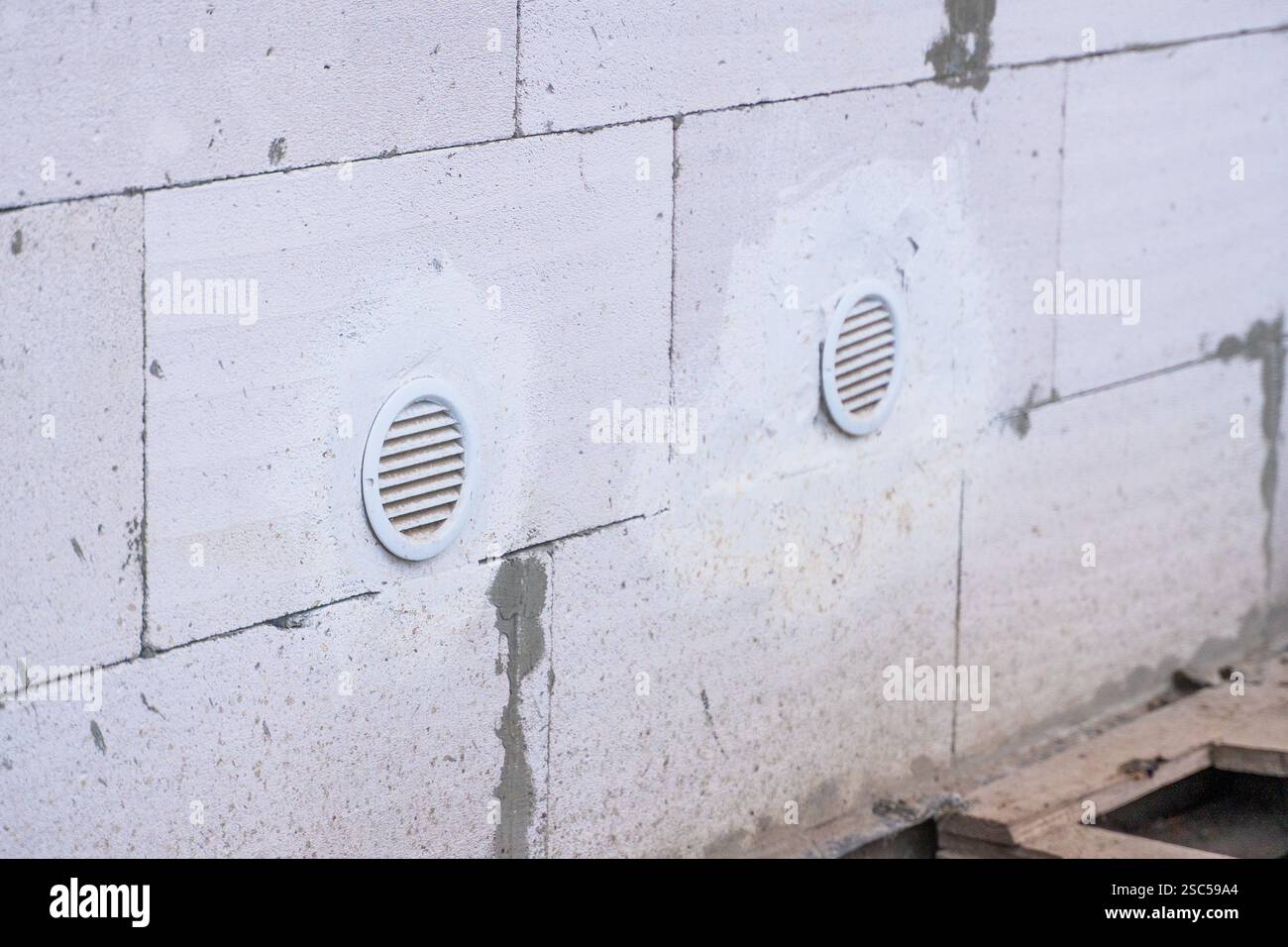 Extractor hole with plastic grille in a wall made of aerated concrete ...