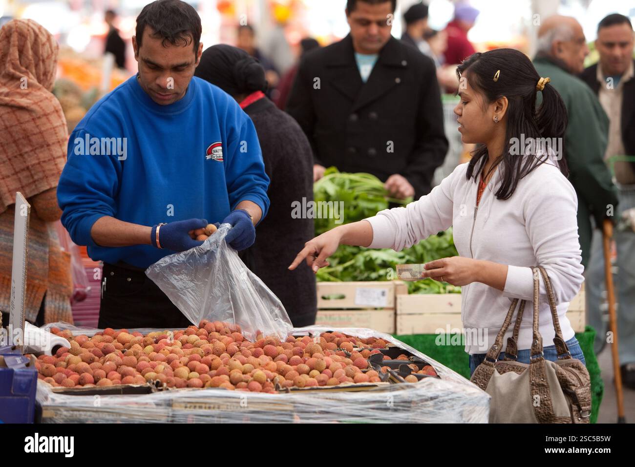 A woman buying lychees at a busy market stall Stock Photo - Alamy