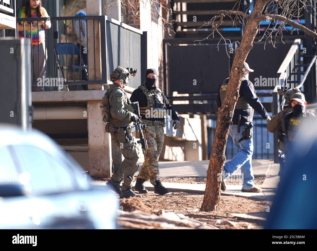 Law officials move through an apartment complex during a raid Wednesday ...