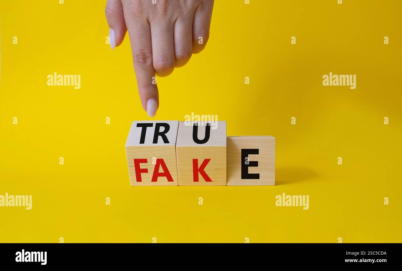 True vs Fake symbol. Businessman Hand points at wooden cubes with words Fake and True. Beautiful ...