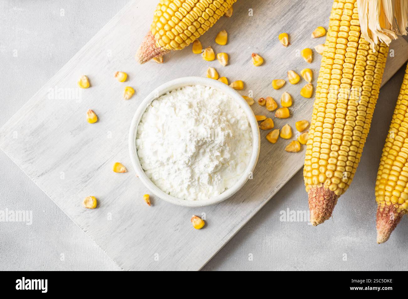 Corn starch in bowl and spoon with dried corn groats, kernels on rustic ...