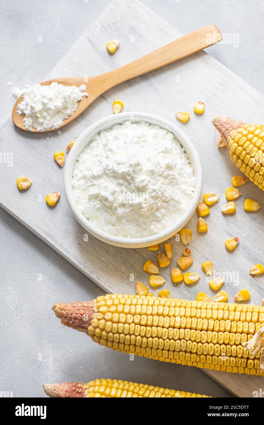Corn starch in bowl and spoon with dried corn groats, kernels on rustic ...