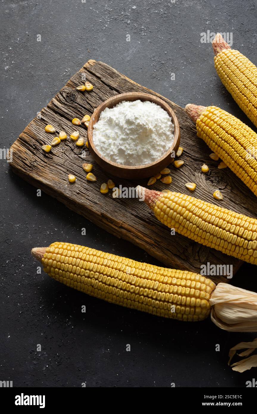 Corn starch in bowl and spoon with dried corn groats, kernels on rustic ...