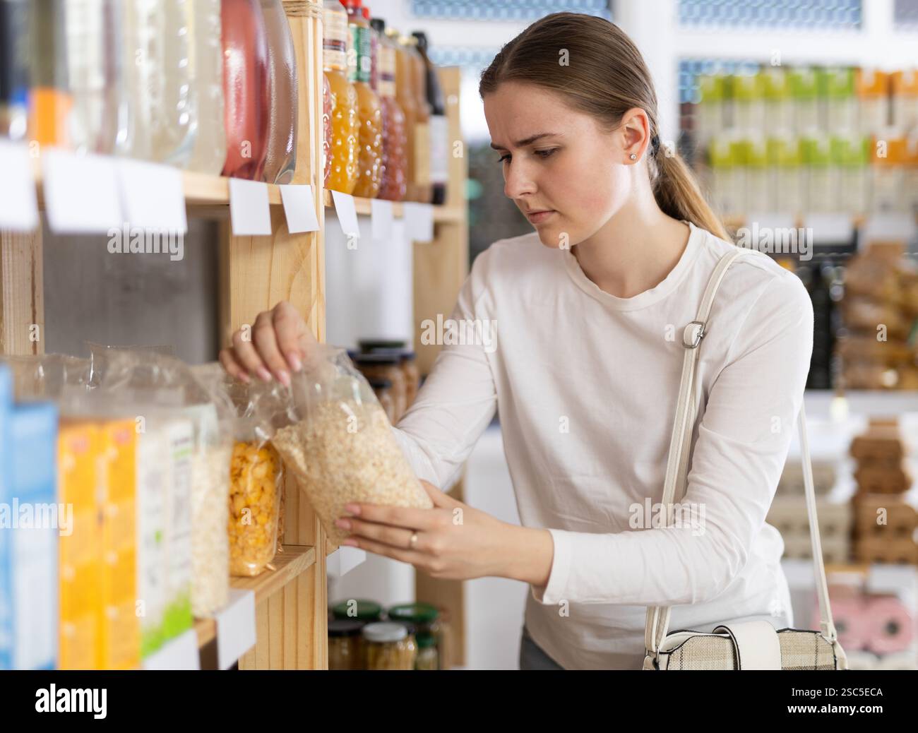 Girl customer in supermarket choose and take flakes from shelve, buy ...