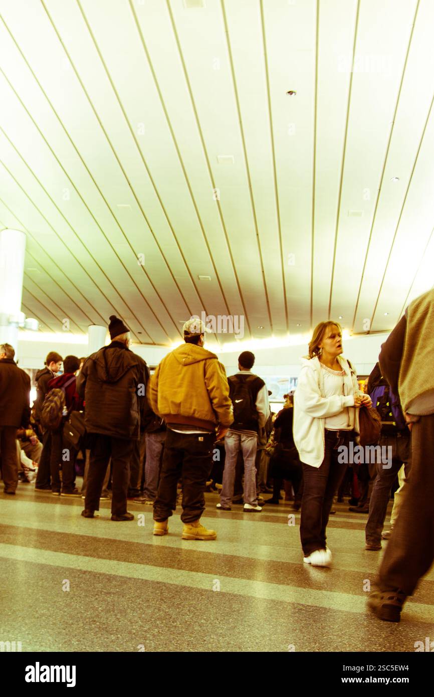 A large crowd of people are waiting or moving through a terminal ...