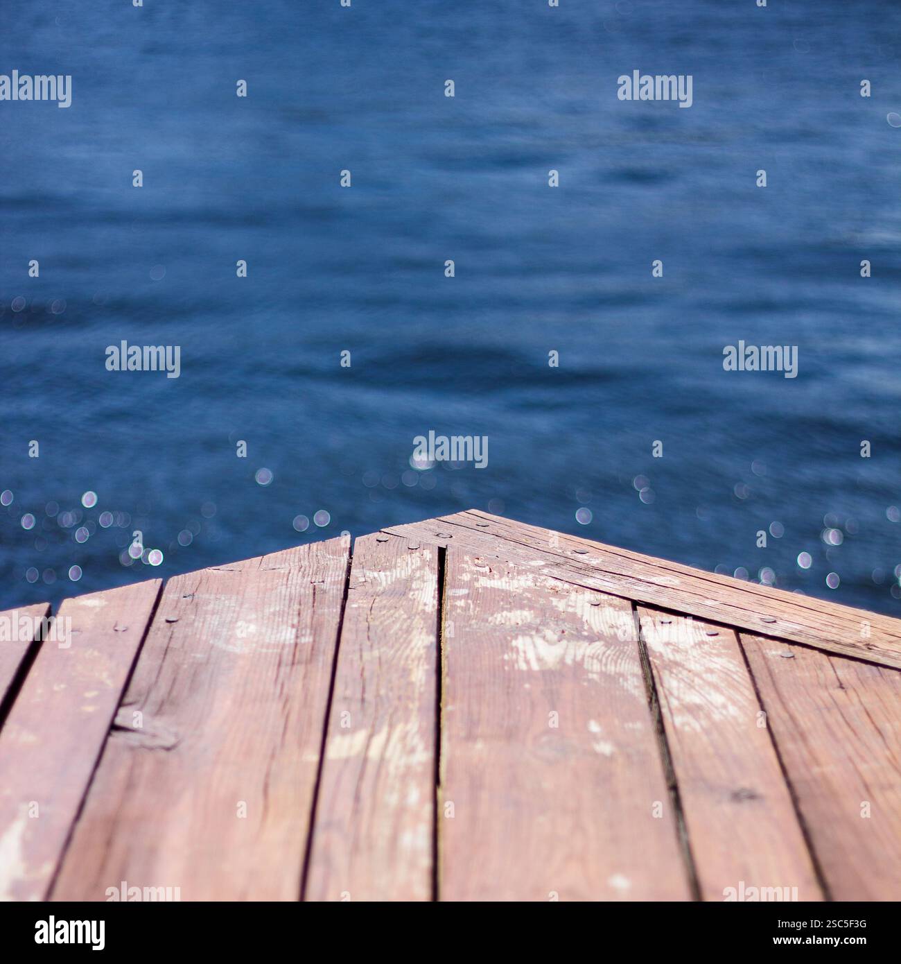 A close-up view of a wooden dock's corner extending out over a body of ...